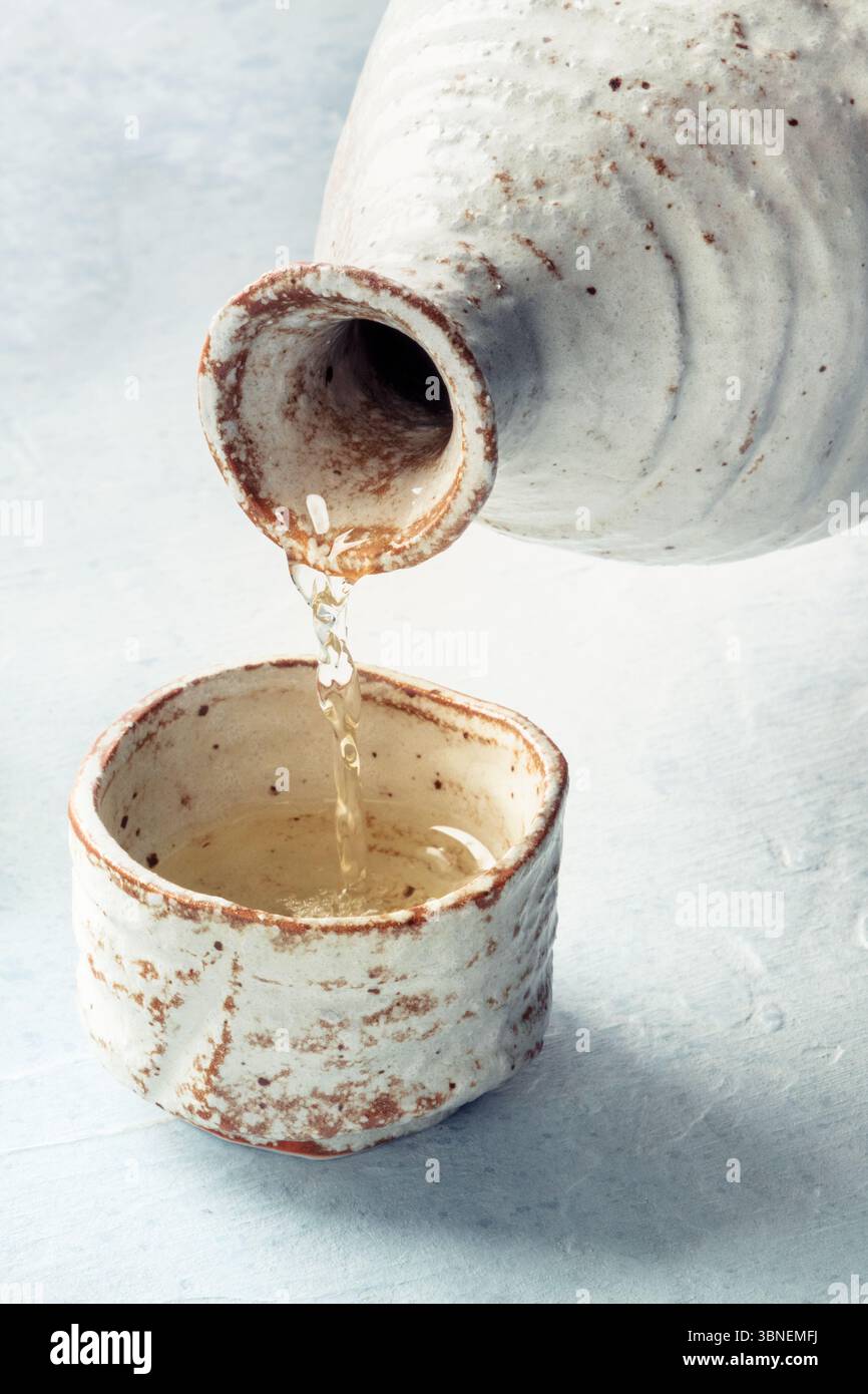 Sake poured into ochoko, traditional cup, on a slate background, a ...