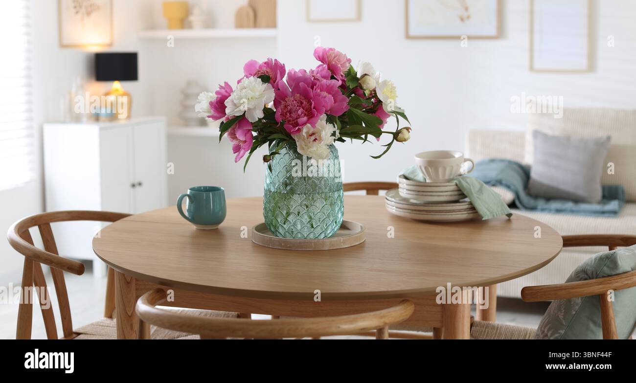 Dining table with beautiful flowers and dishware in room. Interior ...