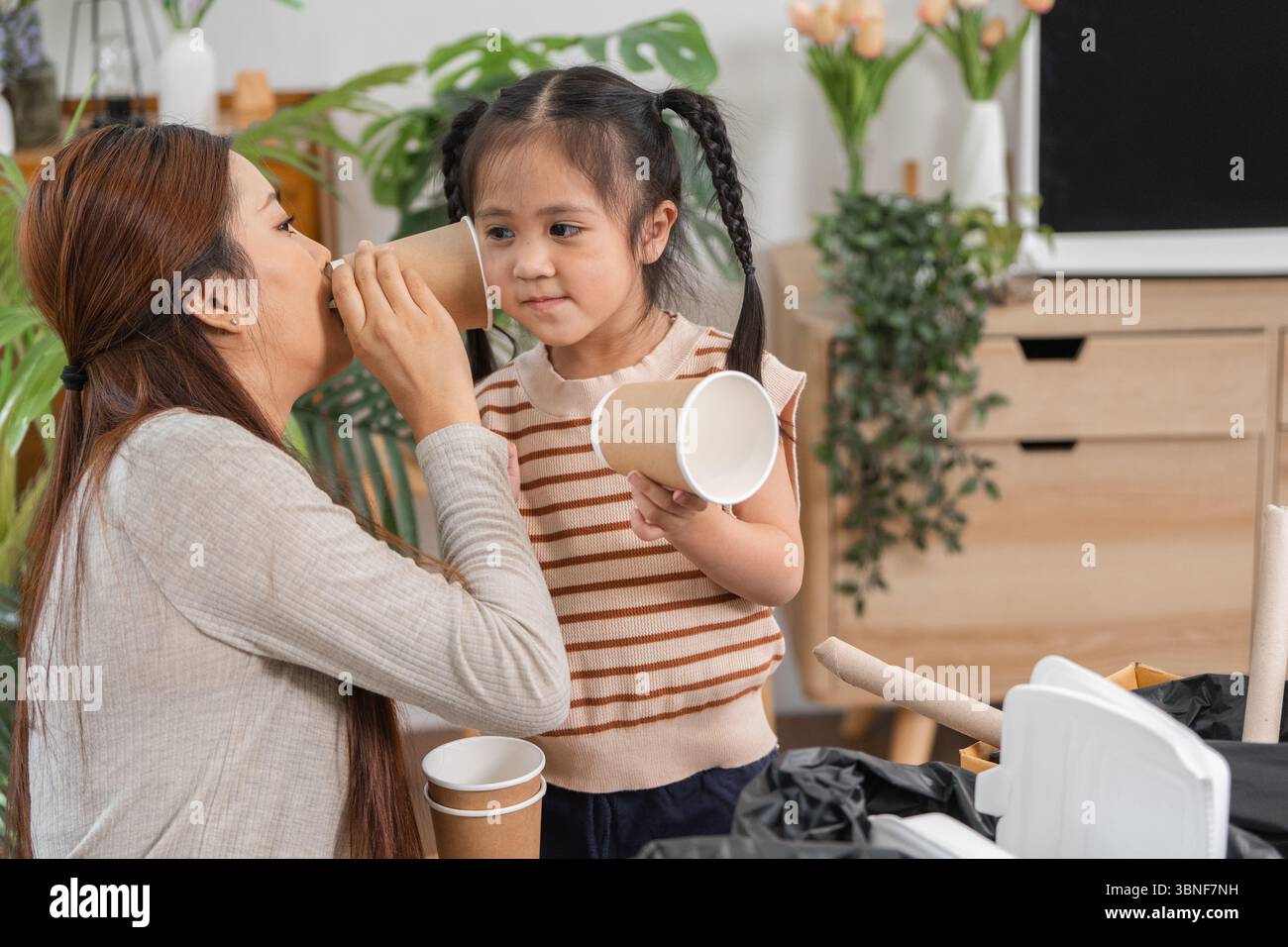 Engaging in Sustainability. A mother and daughter playfully sort recyclables for better waste ...