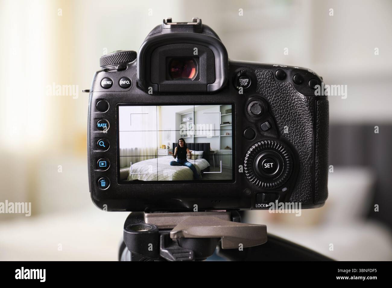 Woman sitting on bed in studio, focus on video camera recording her ...