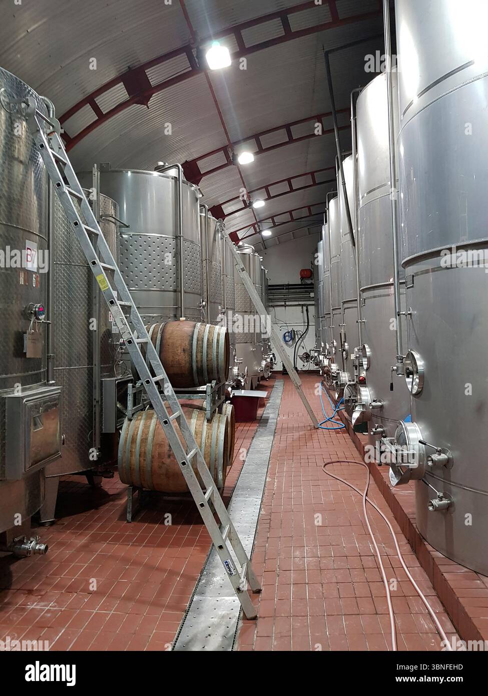Large fermentation tanks and oak barrels are standing inside a modern ...