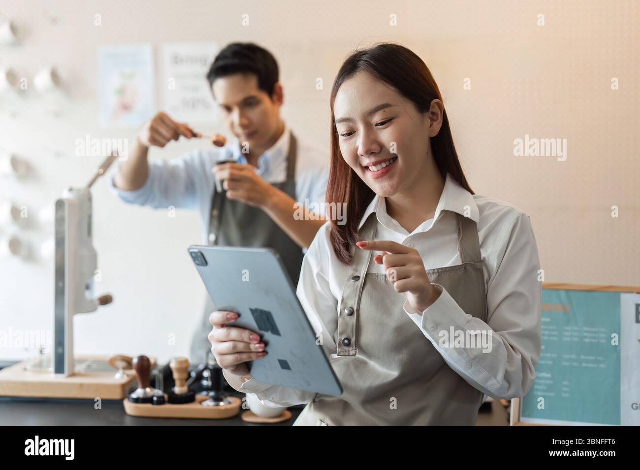 Digital Engagement and Sustainable Coffee. A barista using a tablet to ...