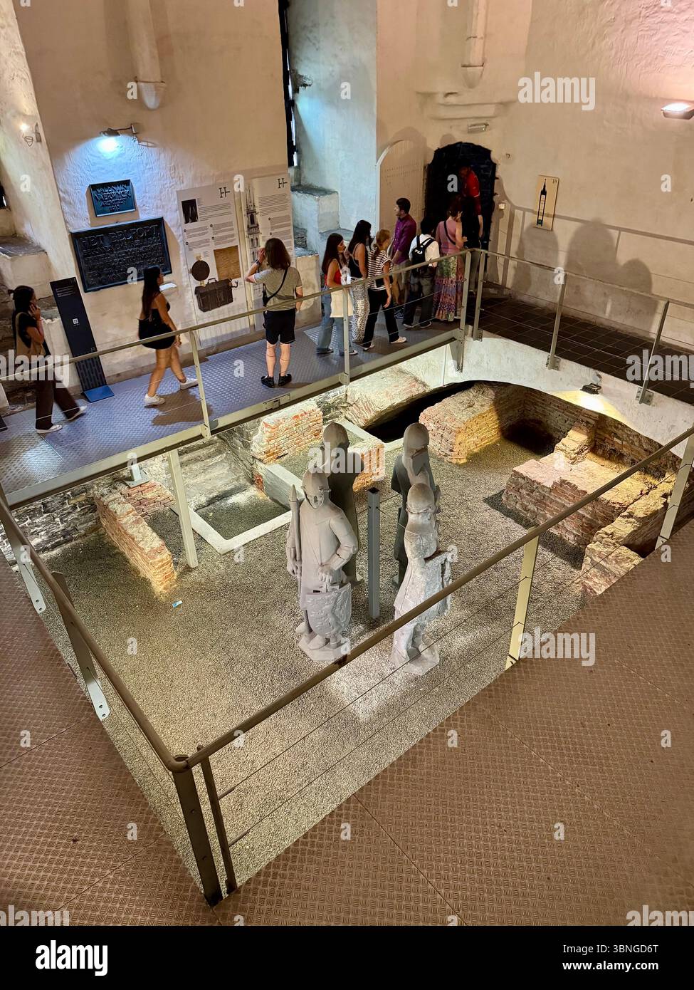 Visitors explore archaeological ruins displayed beneath a glass-floored ...