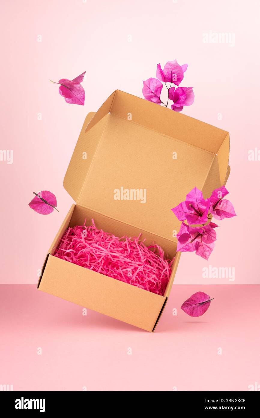 Open cardboard box with bougainvillea flowers on pink background ...
