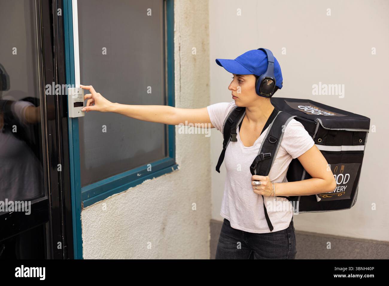 Delivery employee with thermal backpack arrives at the door ringing the ...