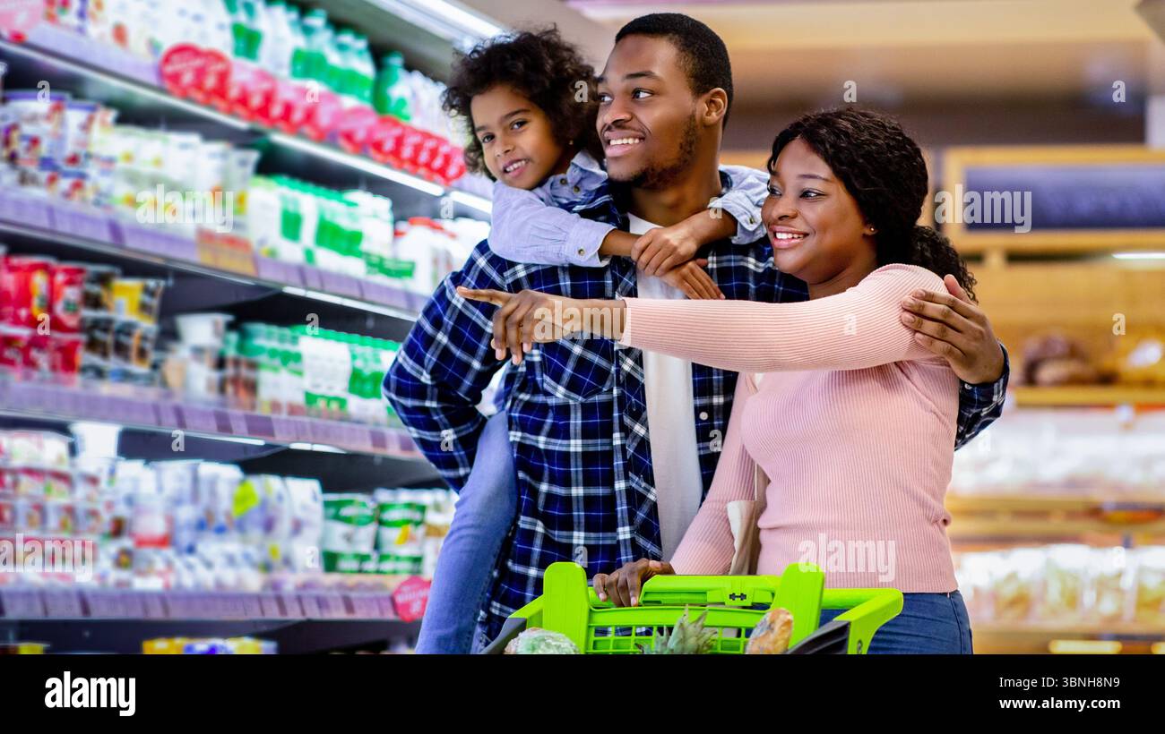 Family shopping. Young black parents with their cute daughter selecting ...
