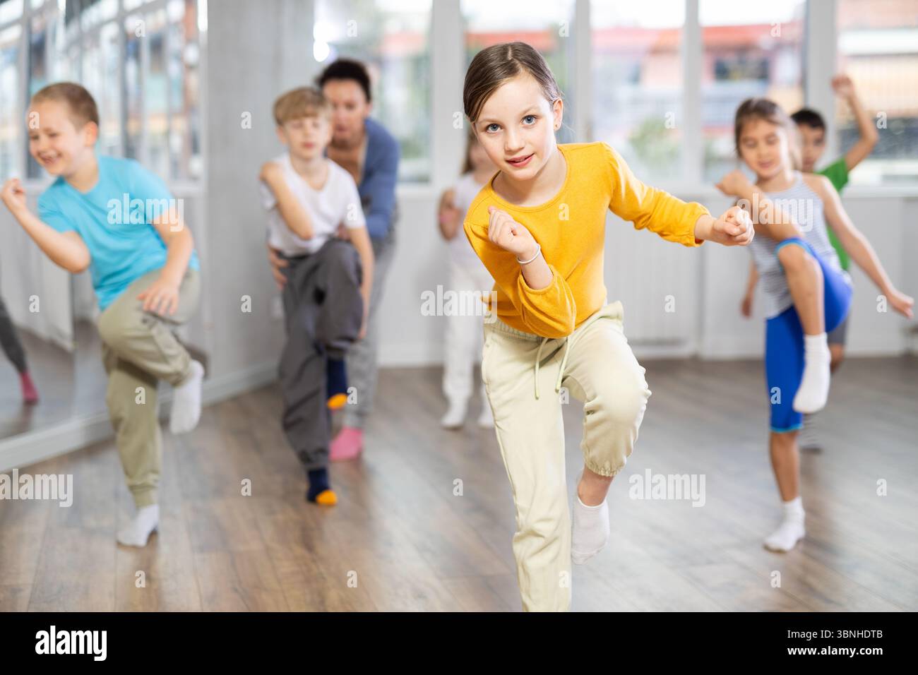 Children studying modern style dances with female teacher in dance ...