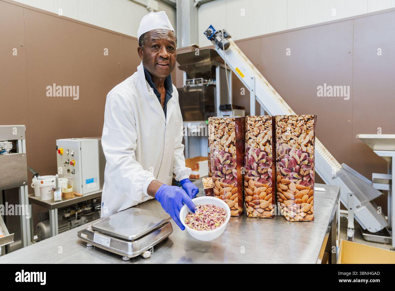Warehouse worker weighing and packaging pistachios in a food processing ...