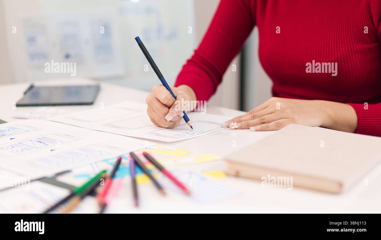 Close-up shot of an Asian adult woman hands drawing a wireframe on ...