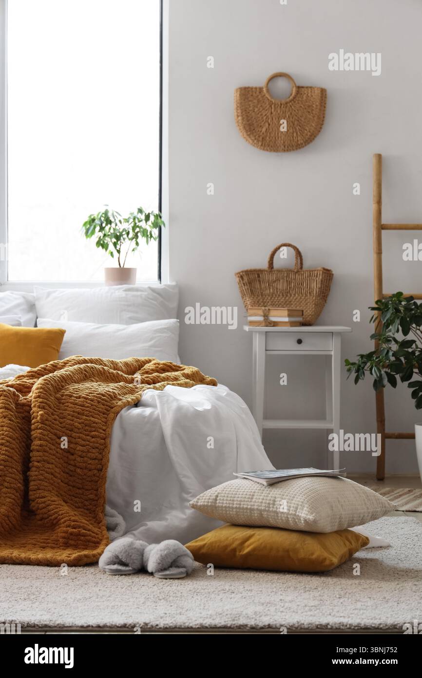 Interior of light bedroom with bedside table, houseplants and cozy bed ...