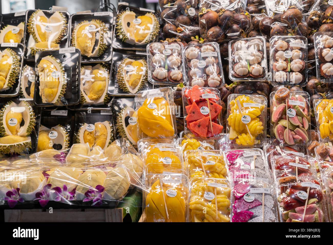 Colorful and neatly arranged display of pre-packaged tropical fruits at ...