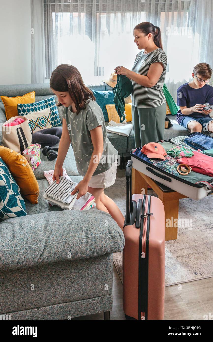 Family packing suitcases and bags for summer vacation in living room ...