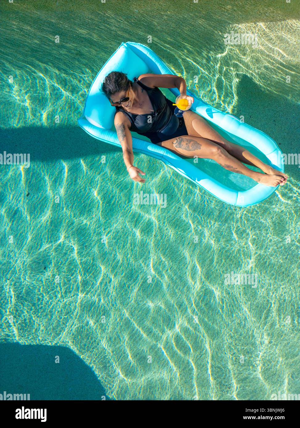 Top aerial view of woman relaxing on an inflatable float in the pool ...