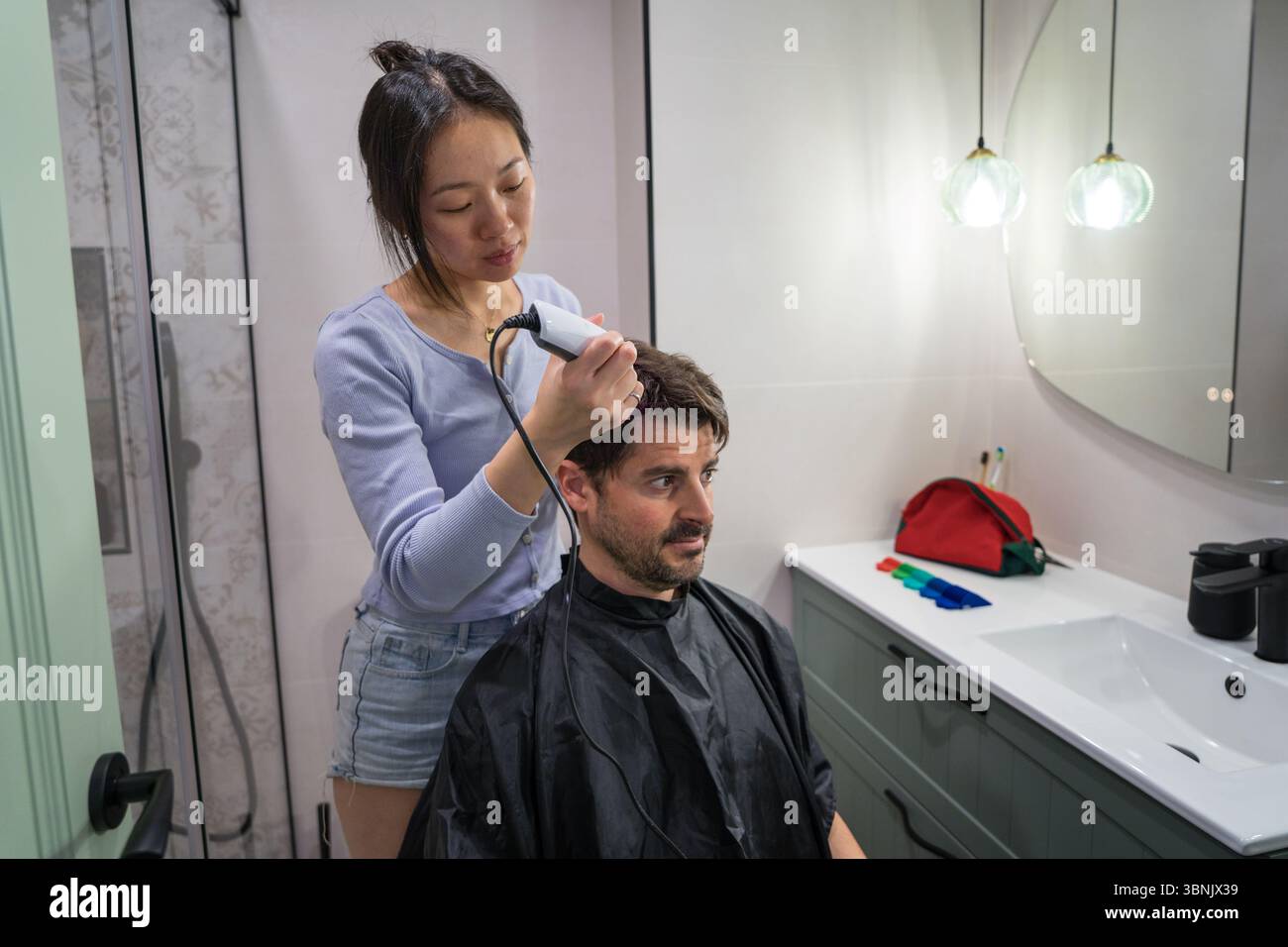 A couple enjoying quality time together during a DIY haircut in a ...