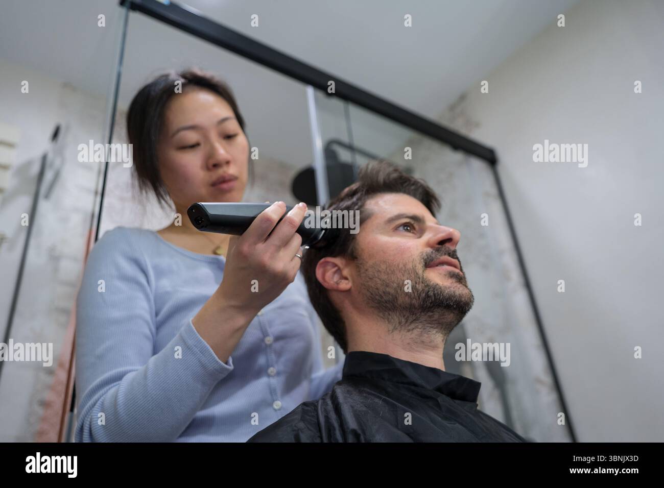A couple shares a personal grooming moment in a modern bathroom, where ...