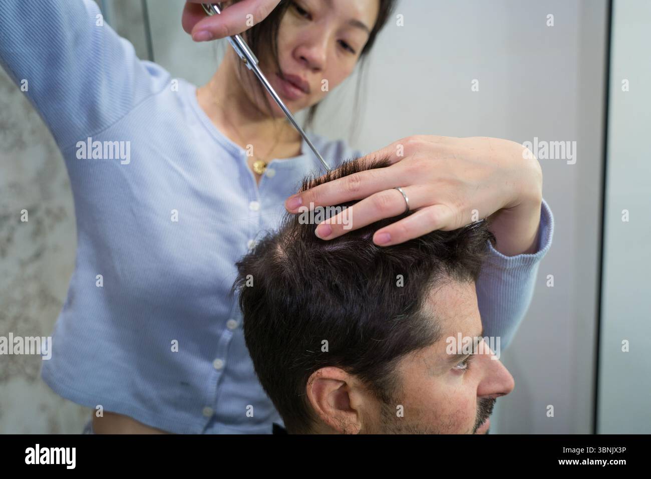 A couple enjoys quality time during an at-home haircut session in a ...