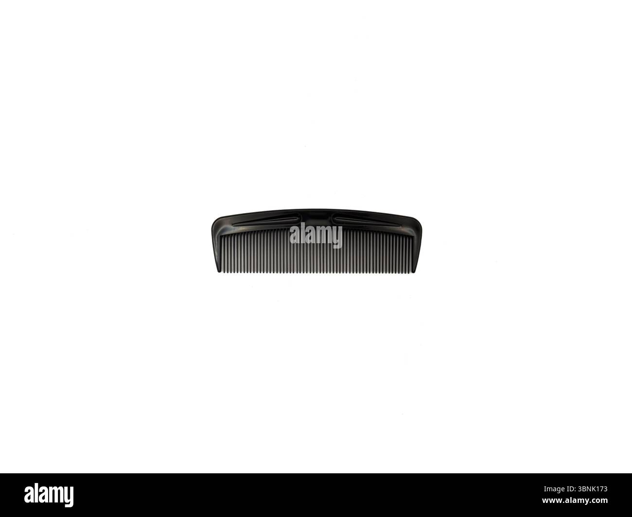 A black comb with a black handle. The comb is laying on a white ...