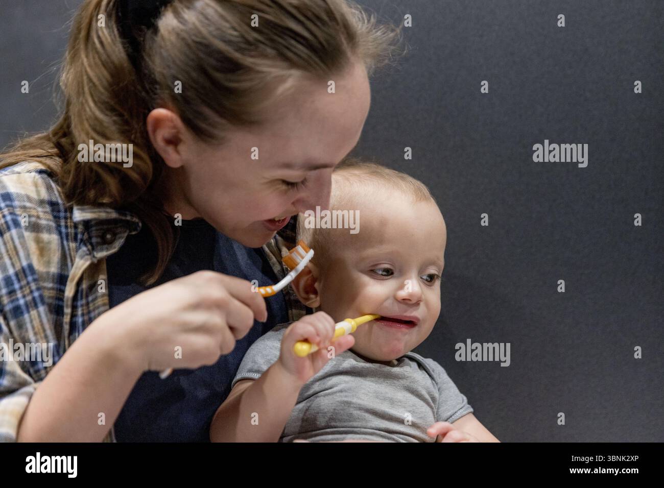 A woman is diligently brushing her teeth while simultaneously holding a ...