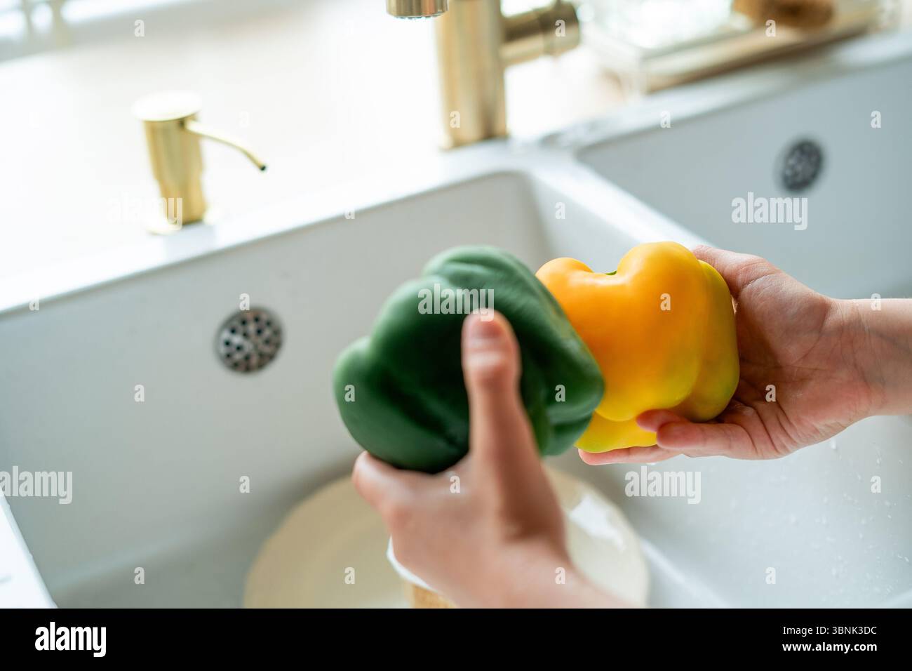 Closeup of small children's hands washing vegetables under the tap in ...