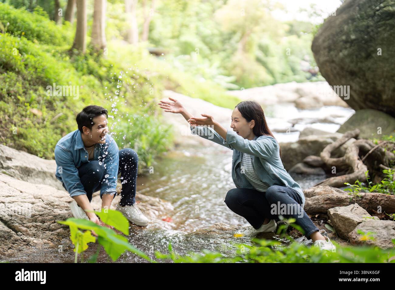 Couple splashing water in stream. Young man and woman enjoying playful ...