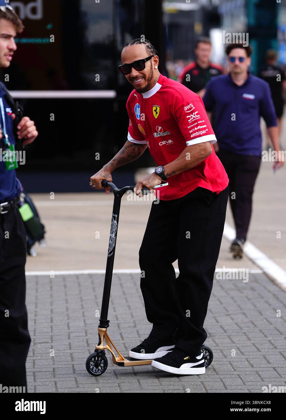 Ferrari driver Lewis Hamilton arrives by scooter at Silverstone Circuit ...