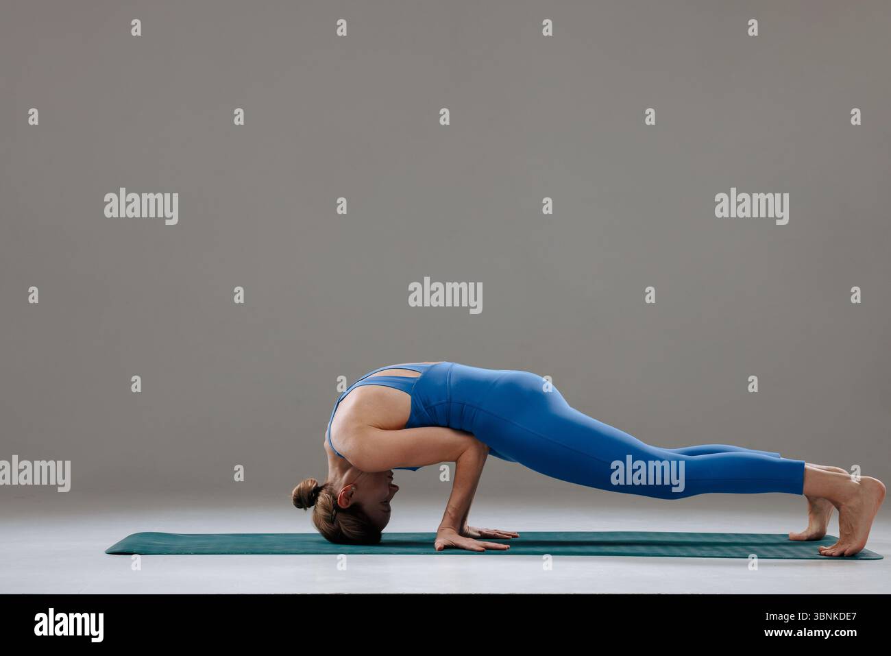 Focused woman performing advanced yoga arm balance pose indoors showing ...
