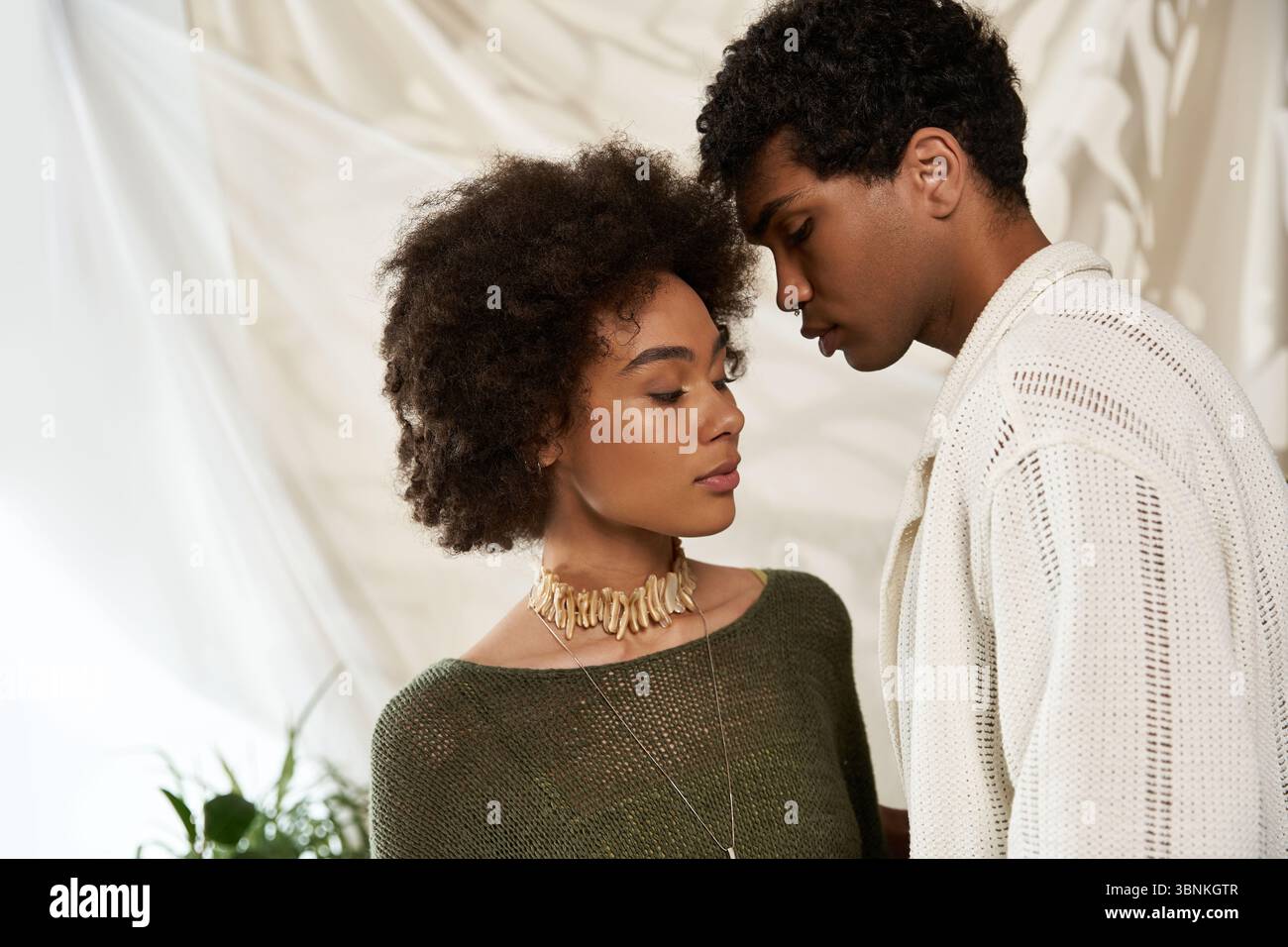 A young couple stands close, radiating love and connection in a stylish ...