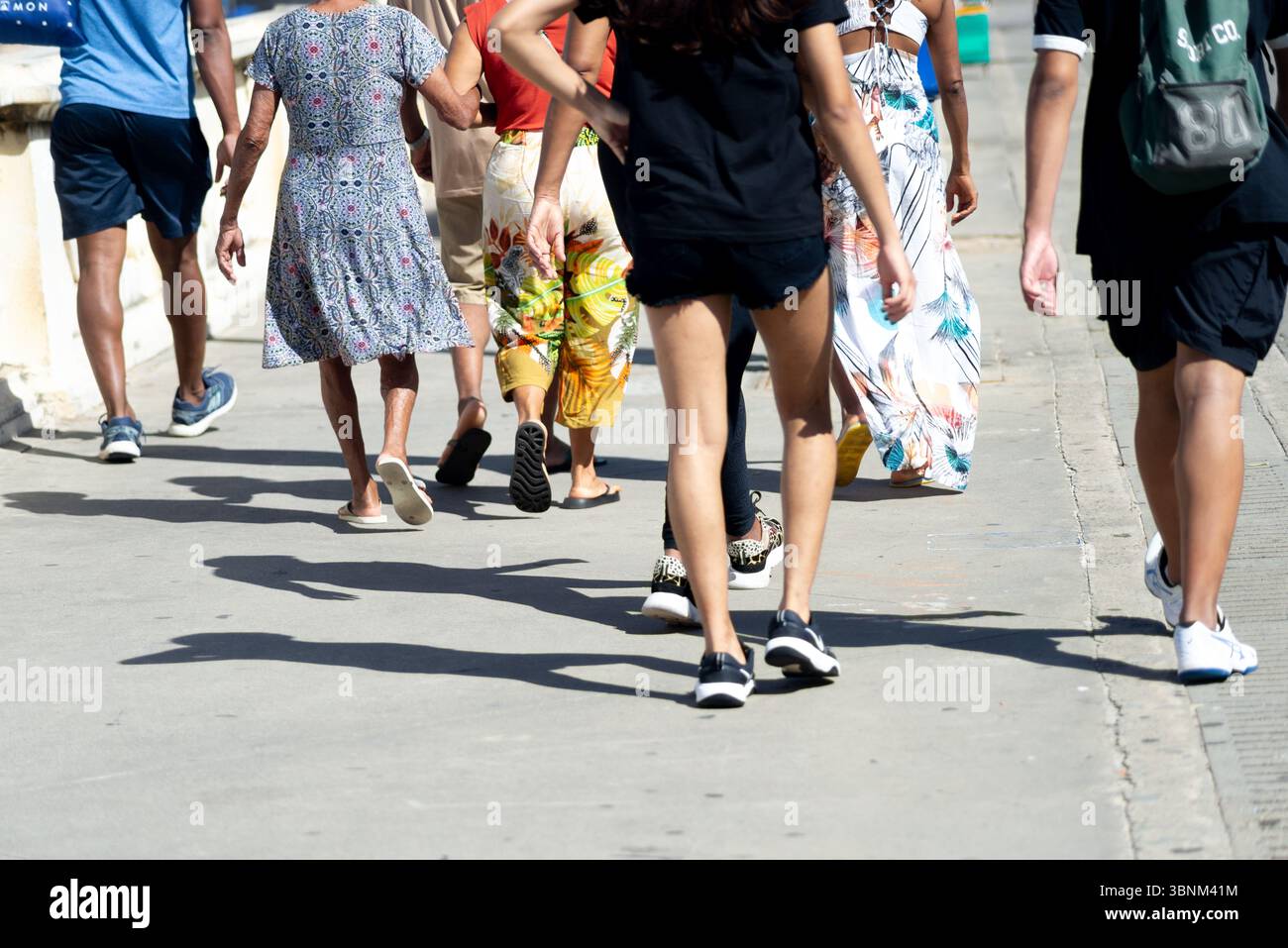 Lower part of unidentified people walking on a paved street ...