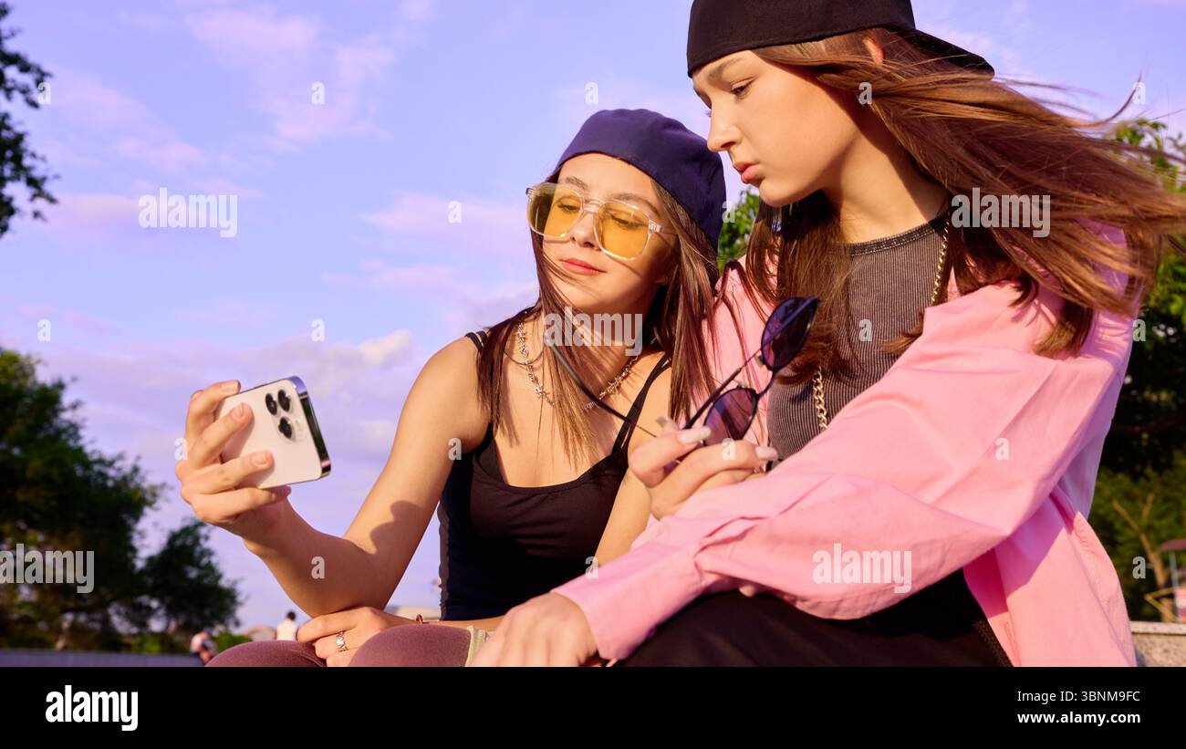 Dance loop. Young women review their dance video on a phone, outdoors ...