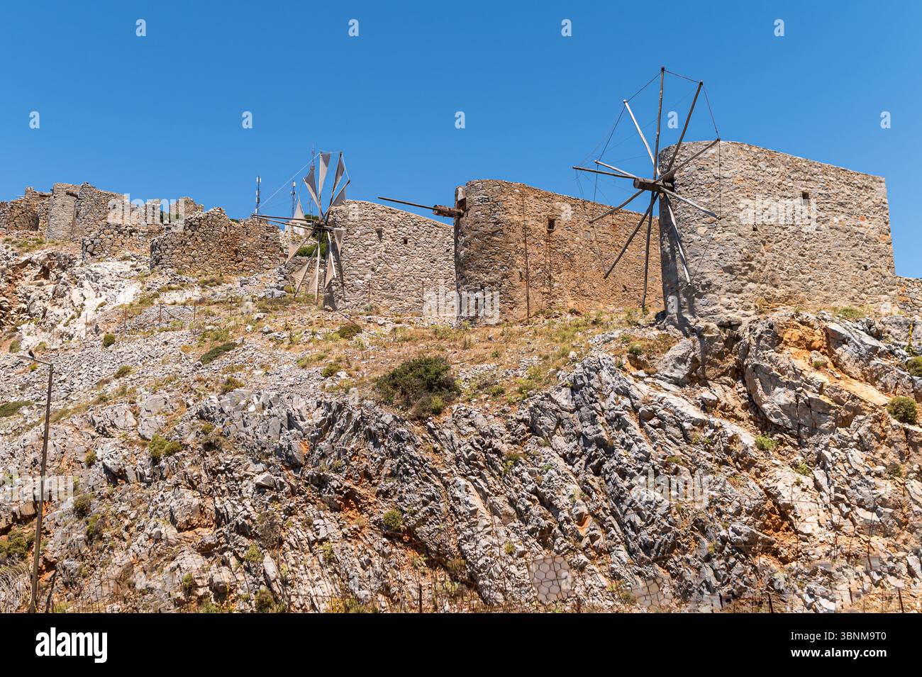 Ancient windmills stand atop rugged cliffs in Crete, showcasing the ...