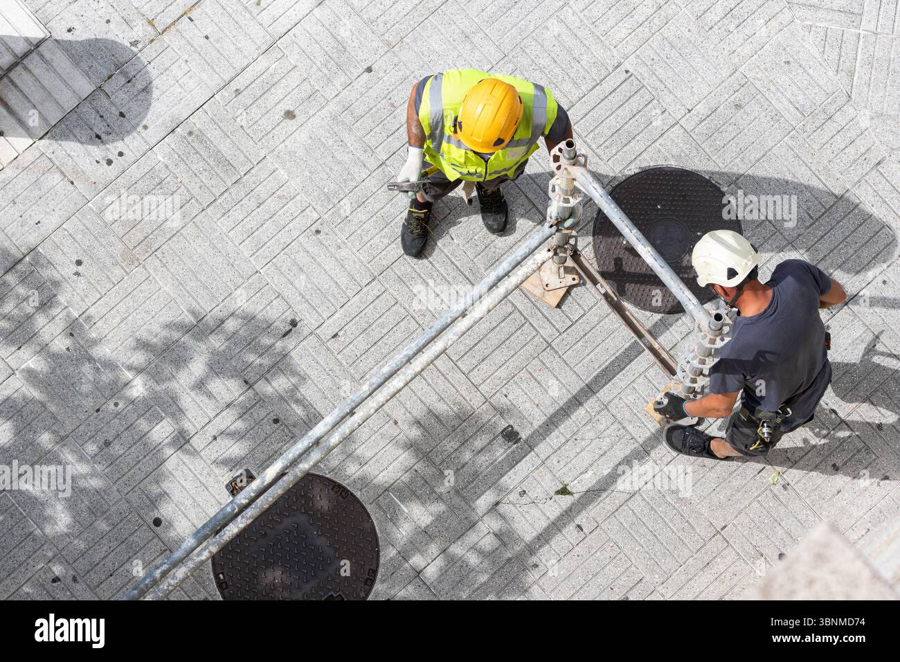 Aerial view of two construction workers assembling scaffolding on a ...