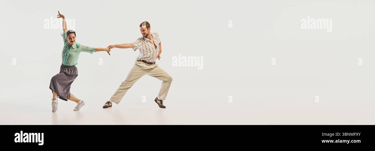 Swing dance duo performing energetic retro routine on plain white ...