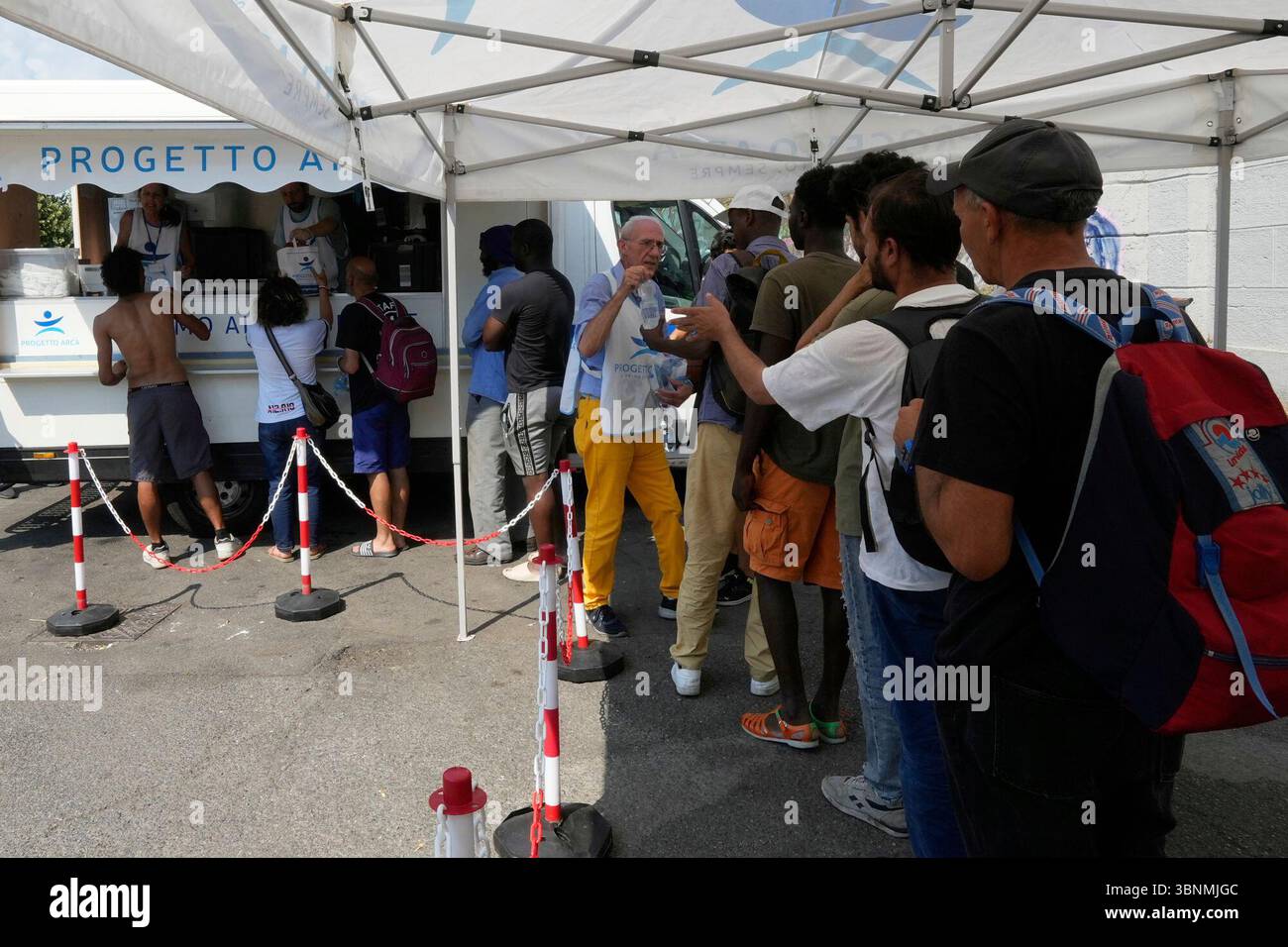 Volunteers distribute food and water to homeless people at the Progetto ...