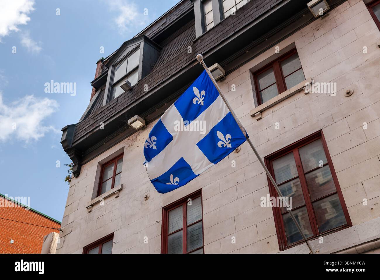The Quebec flag flying from a building in Old Montreal Stock Photo - Alamy