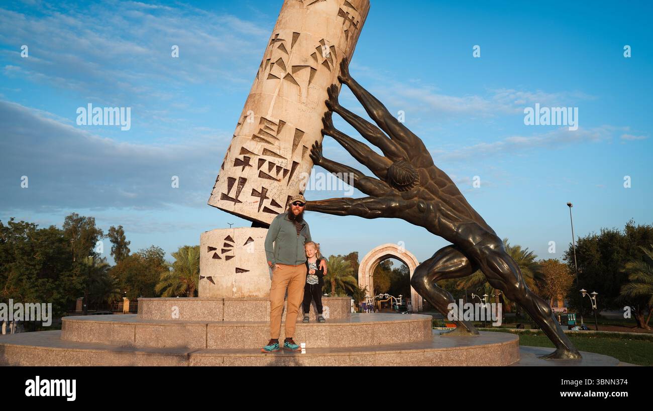 A tourist stands near a large sculpture in a park in Iraq, exploring ...