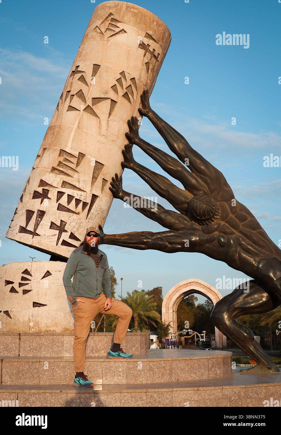 Tourist poses confidently beside a striking monument featuring powerful ...