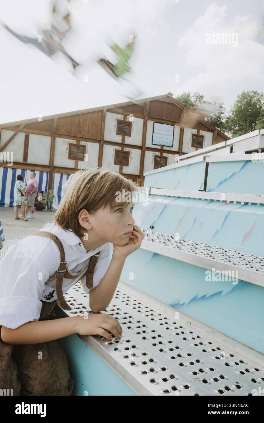 Boy sitting on the steps of a swing carousel at a fair Stock Photo - Alamy