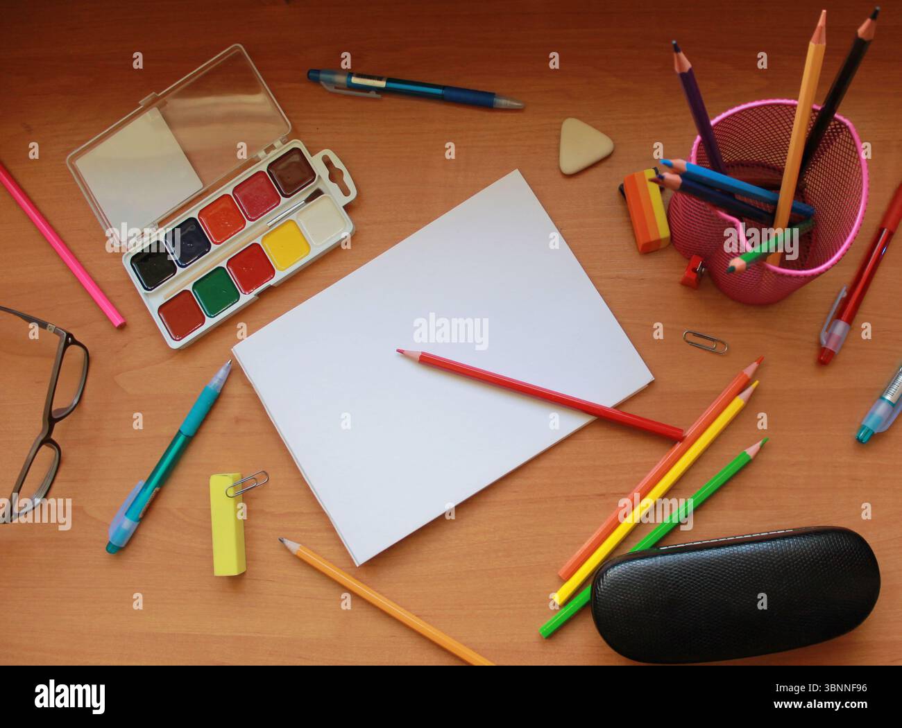 School supplies on a wooden table. Watercolor paints, glasses, pens ...