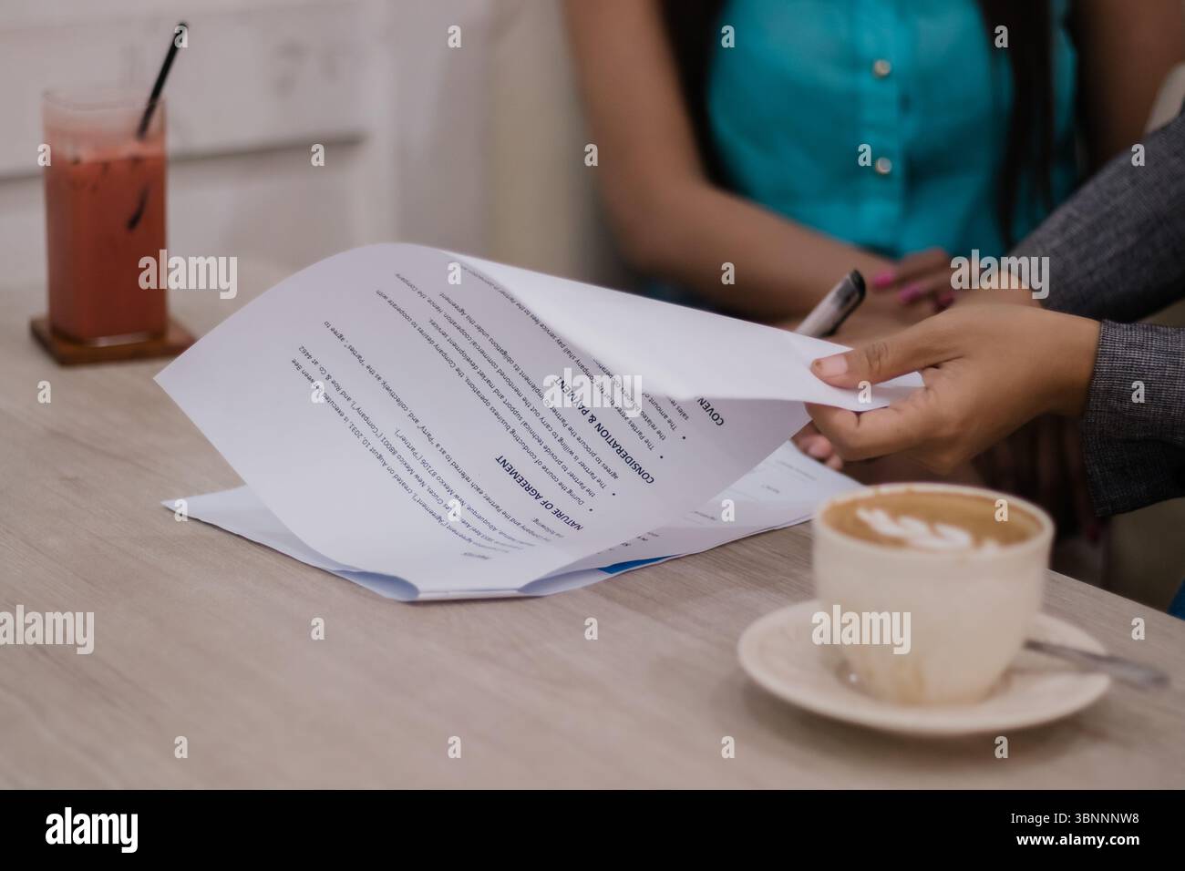 Two professionals are reviewing a contract during a relaxed business ...