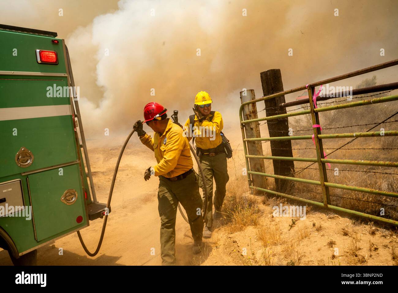 U.S. Forest Service firefighter Alan Gudino, right, shields his face ...