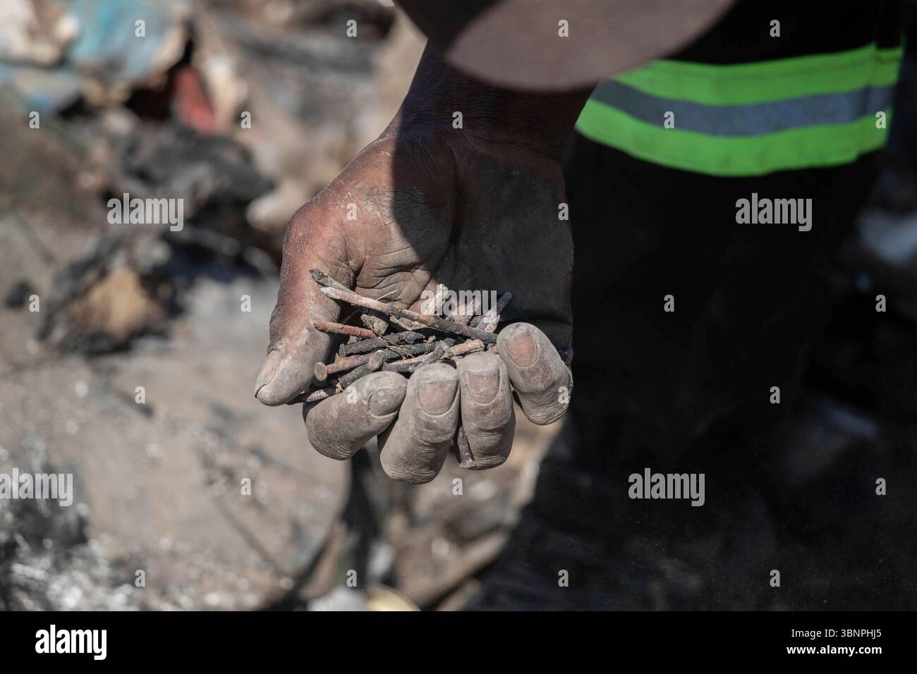 A scrap metal collector holds nails as they work in Harare, Zimbabwe ...