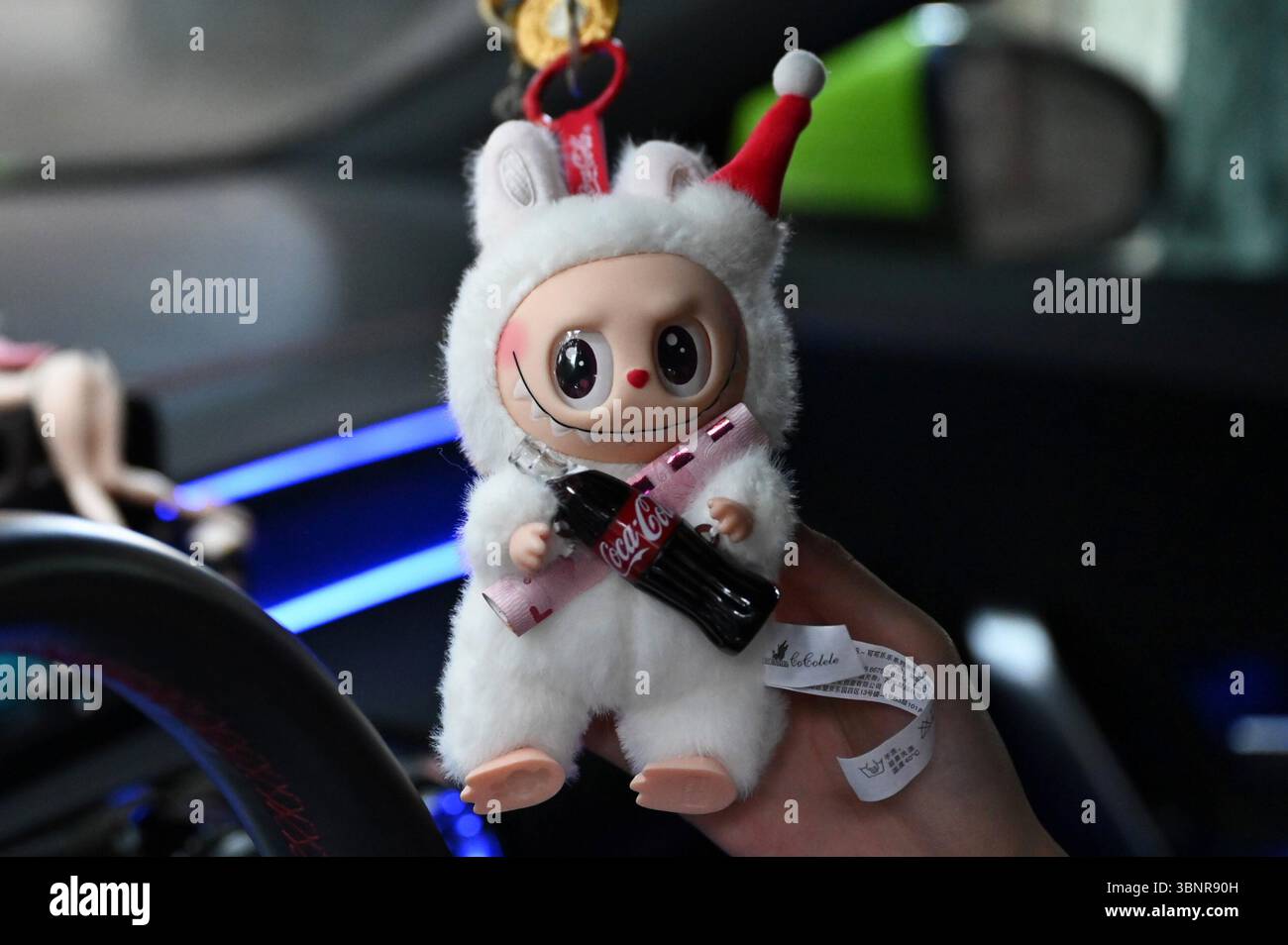 03 July 2025, China, Peking: A woman in a car holds a Labubu figure of ...