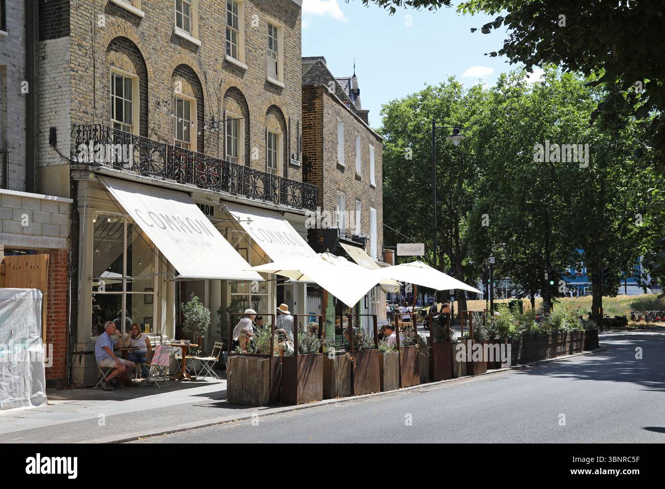 Clapham, London, UK. Open-air tables at restaurants on The Pavement, a ...