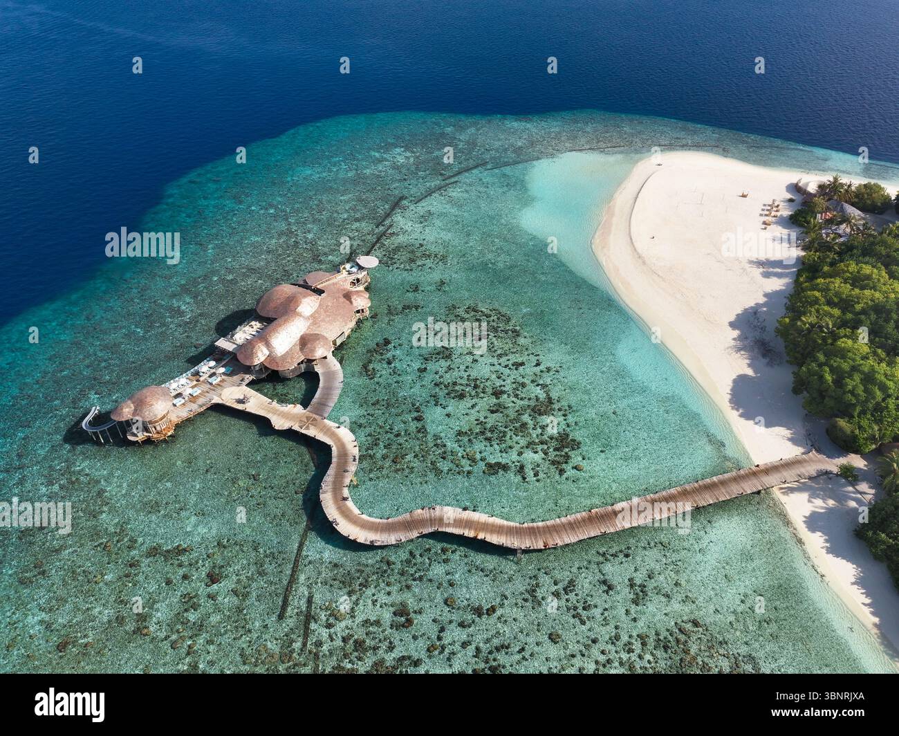 Aerial view of a resort bar and sundeck embrace a pristine white beach ...