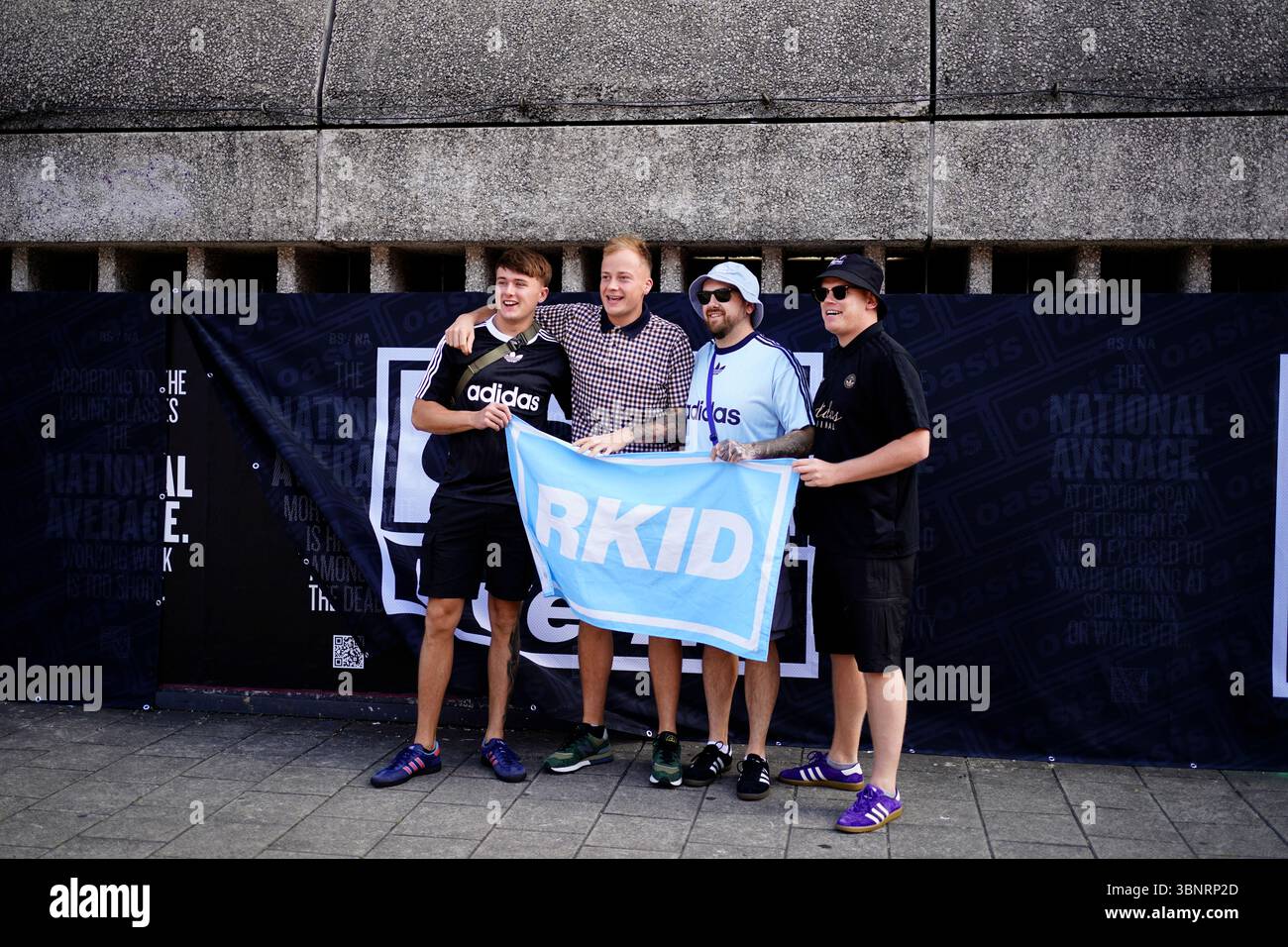 Oasis fans pose for pictures with an "Rkid" banner outside the ...
