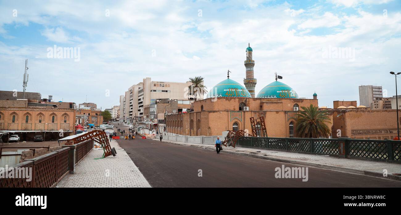 A lively street in Baghdad features a beautiful mosque with blue domes ...