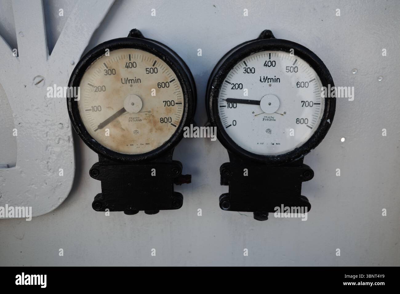 A close-up of two vintage analog flowmeter gauges mounted on a piece of ...