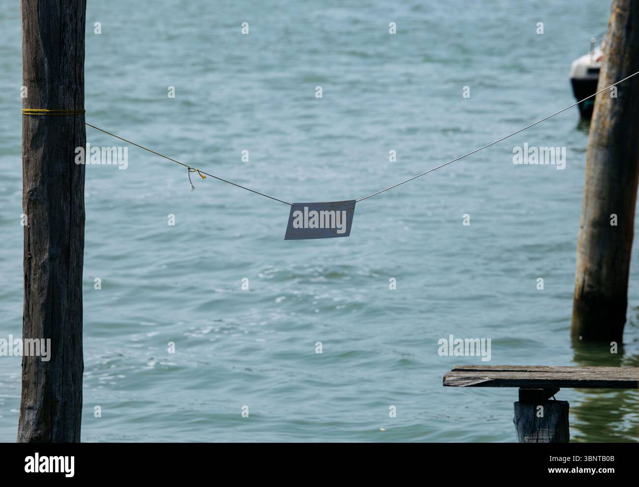 Seaside rope warning sign between wooden poles by the water Stock Photo ...