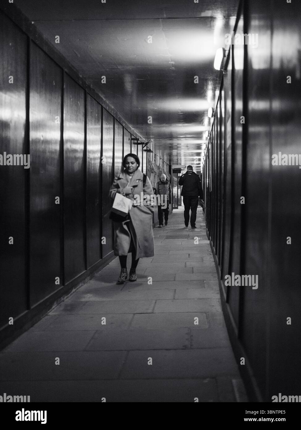 United Kingdom, London, 11 Dec 2024. A woman walks through a narrow ...