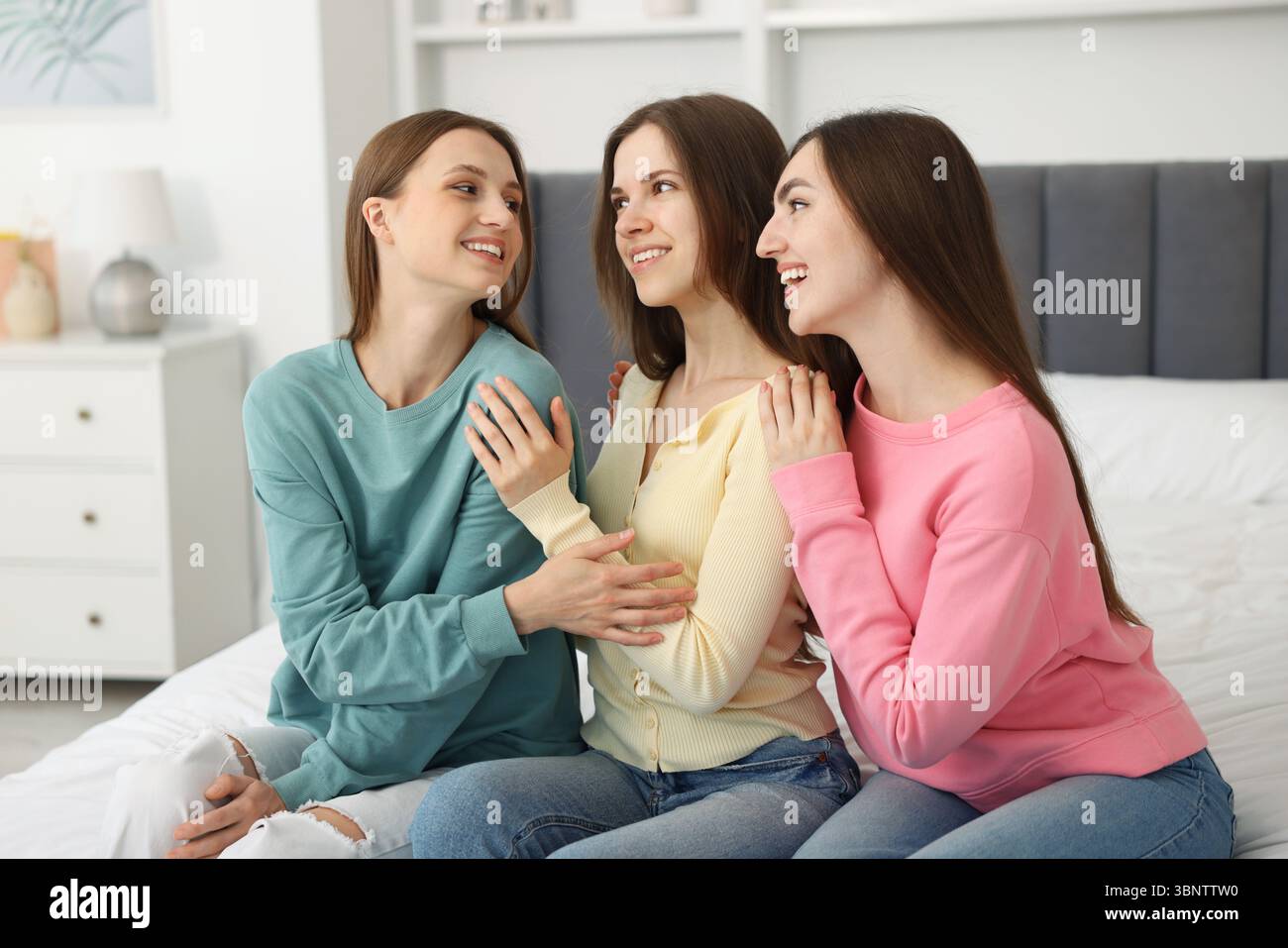 Happy friends hugging each other on bed at home Stock Photo - Alamy
